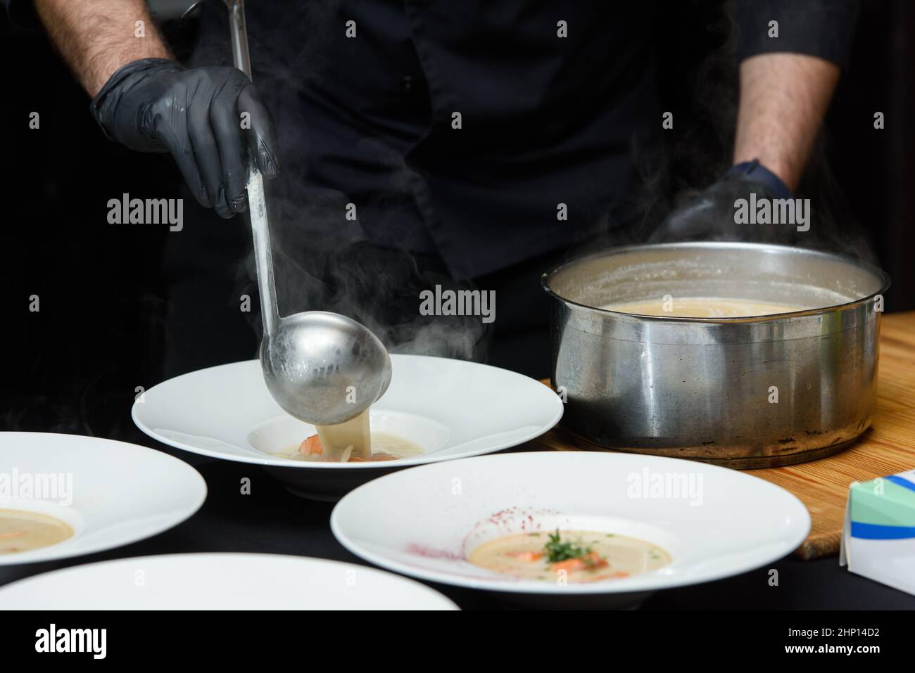 Chief cooking fish cream soup with salmon, cheese and herbs in white ...