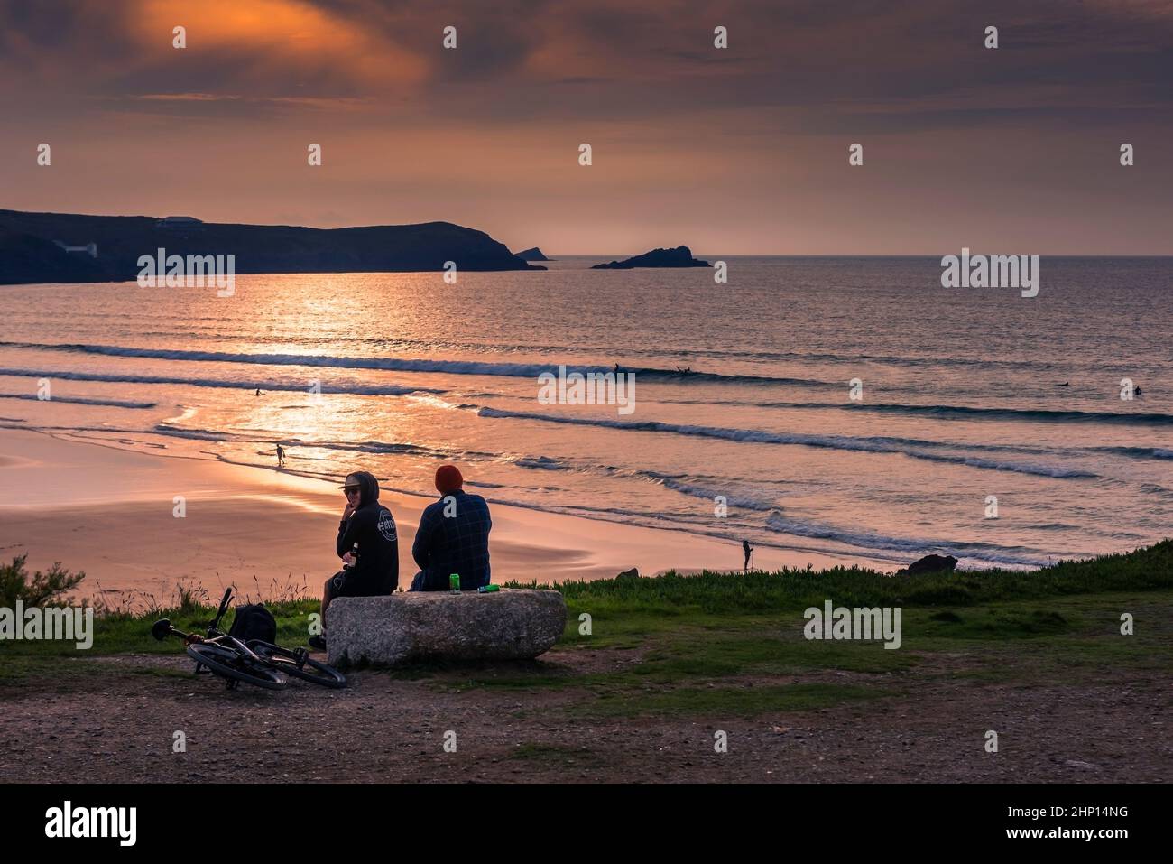 Two friends enjoying a beautiful sunset over Fistral Bay in Newquay in ...