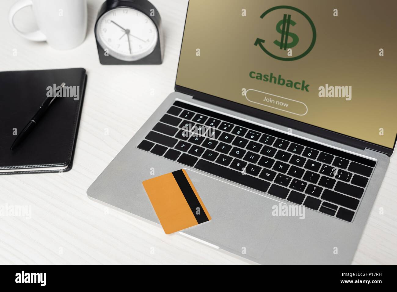 credit card on laptop with cashback on screen near notebook and cup on ...