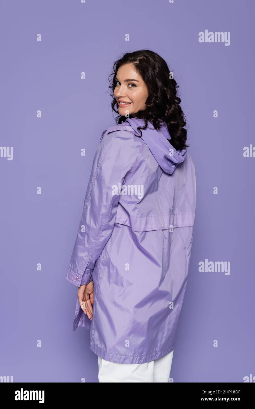 cheerful young woman in violet raincoat isolated on purple Stock Photo ...