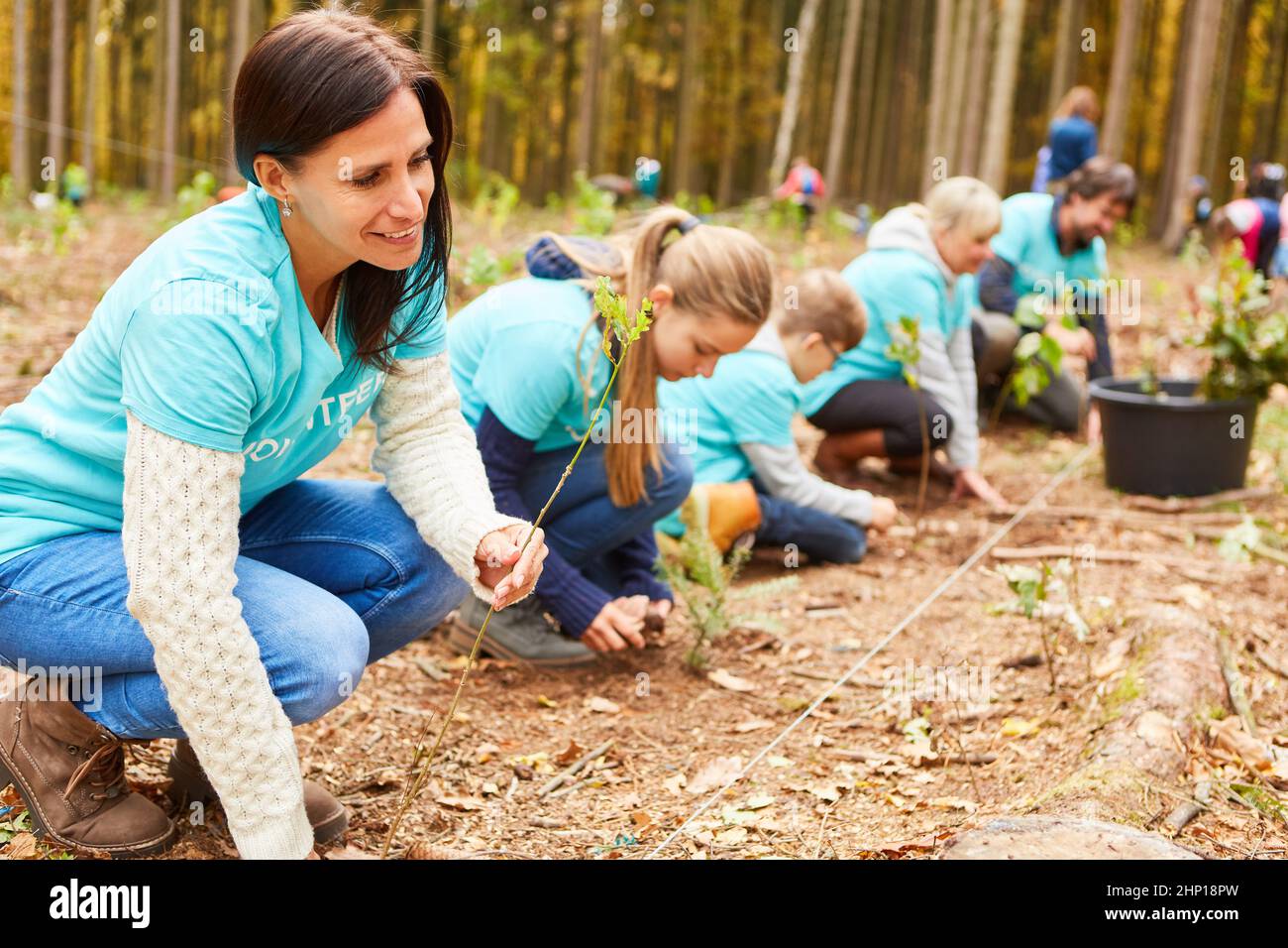 Family and children planting a tree in the forest during a voluntary ...