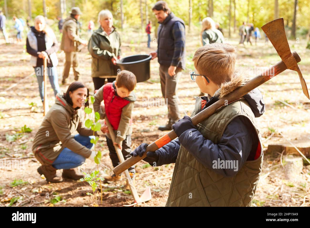 Family and volunteers plant trees together at an environmental ...
