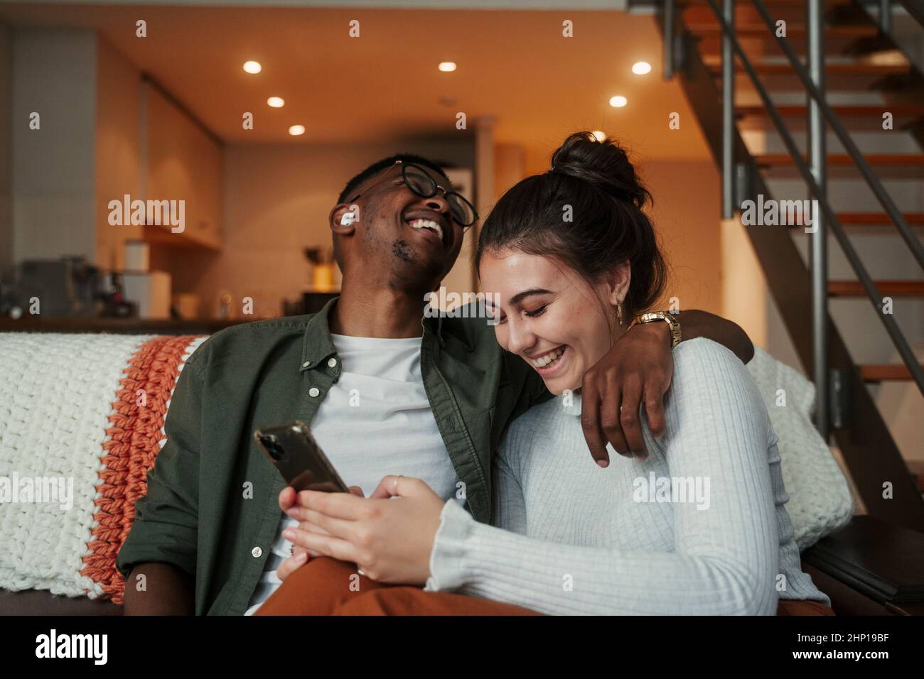 Biracial couple laughing while texting on cellular device Stock Photo ...