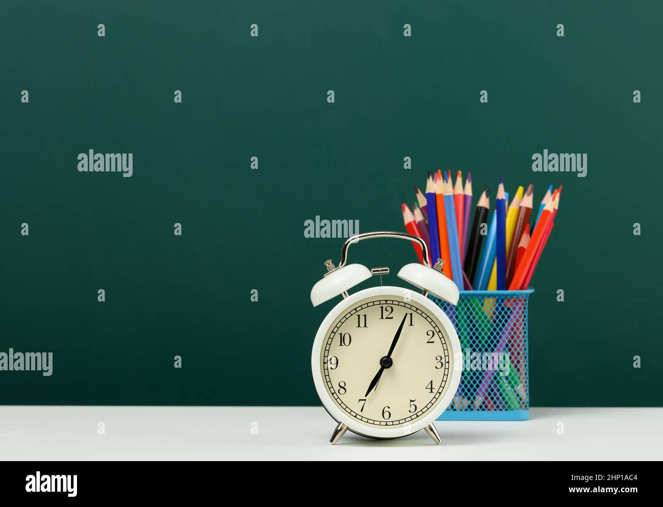 round alarm clock and multicolored pencils on the background of an ...
