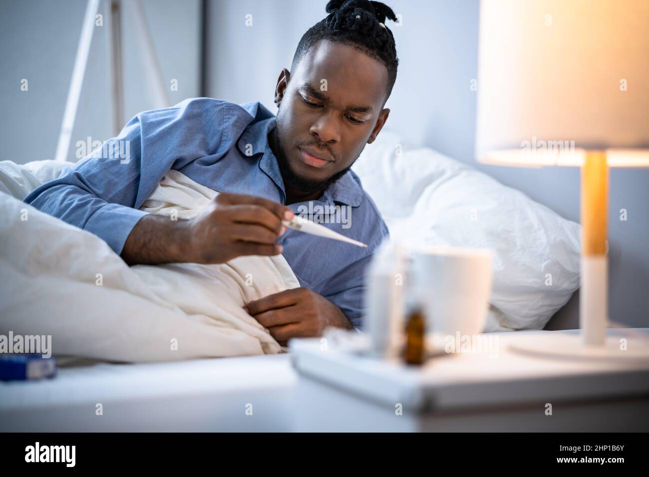 Sick Man With Fever Using Thermometer In Bed Stock Photo - Alamy