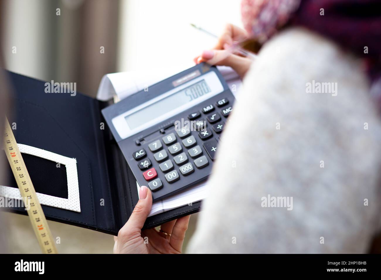 Unrecognizable woman in upper garments making calculations using ...
