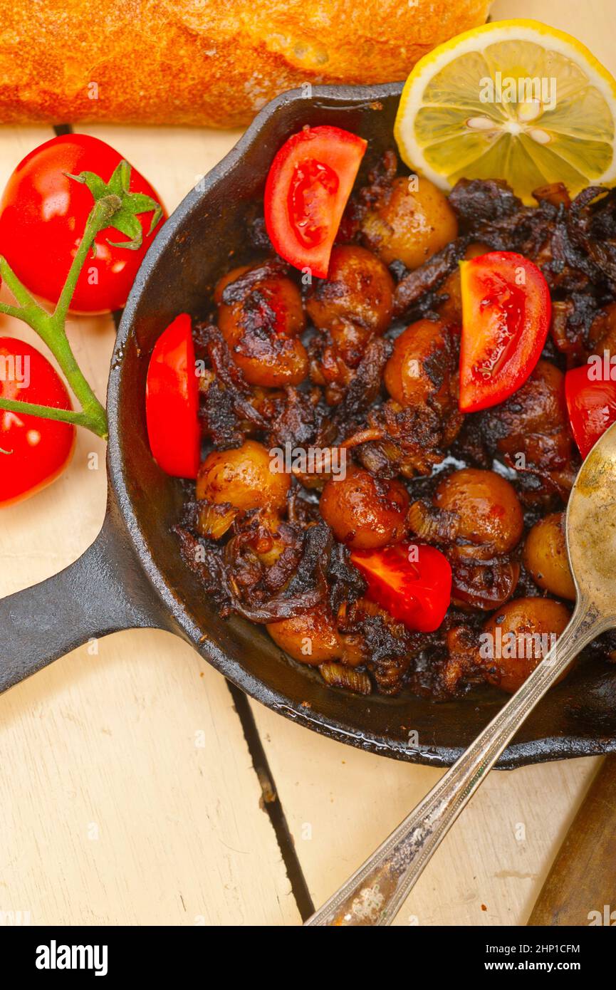 Baby cuttle fish roasted on iron skillet with tomatoes and onions over ...