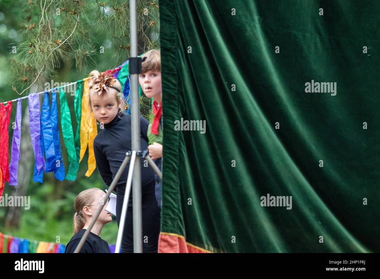 Two very small extras look round a curtain to watch action on stage ...