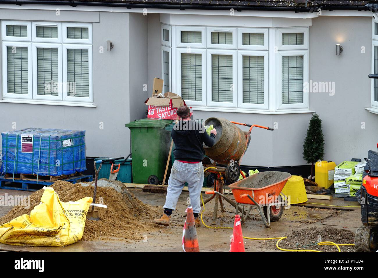 A builder using a cement mixer outside a private house undergoing ...