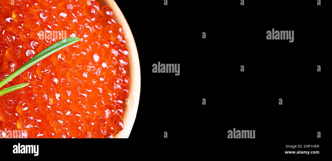 Red caviar in a white cup on a black background. Place for ...