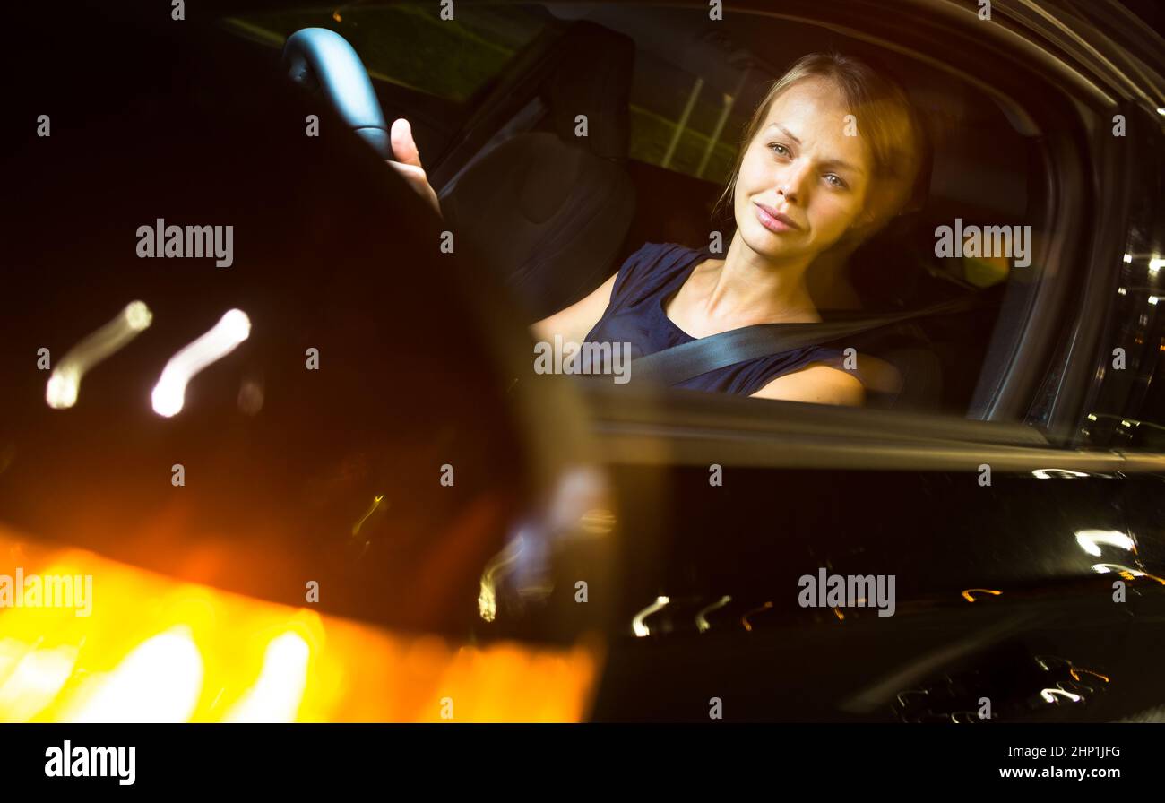 Driving a car at night - pretty, young woman driving her modern car at ...
