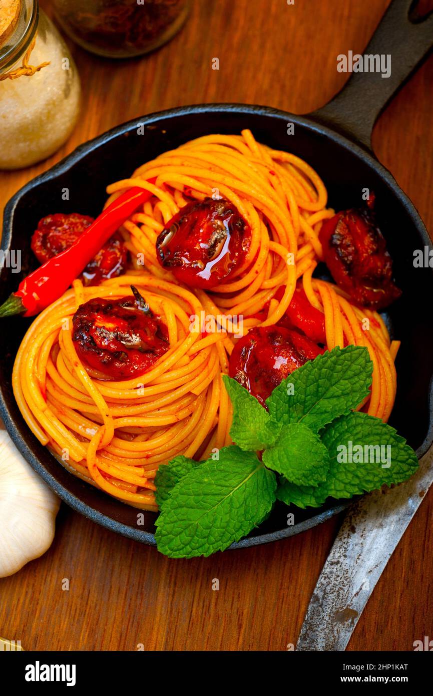 italian spaghetti pasta and tomato with mint leaves on iron skillet ...