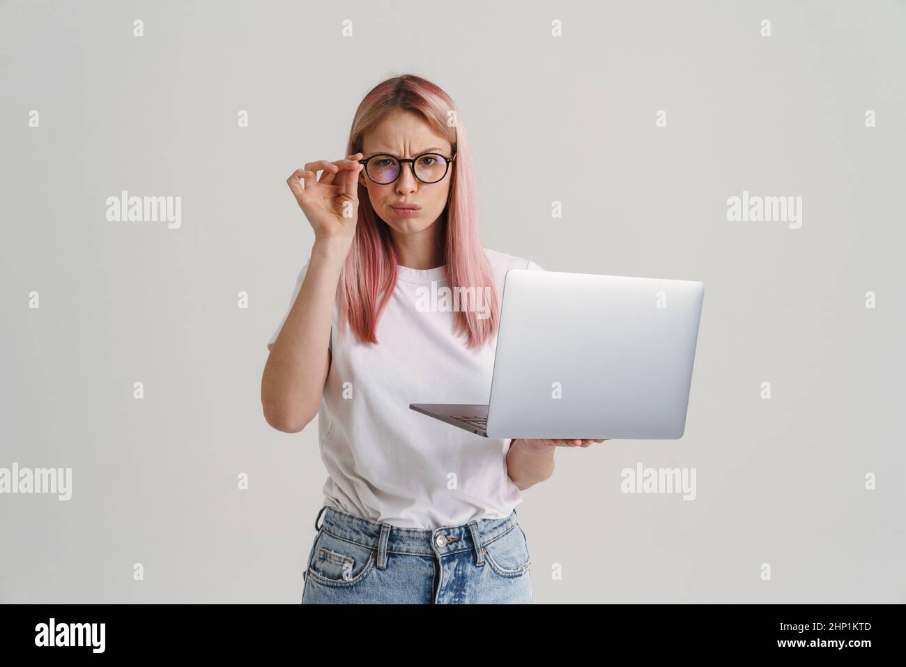 Frowning upset young blonde white woman in glasses standing holding ...