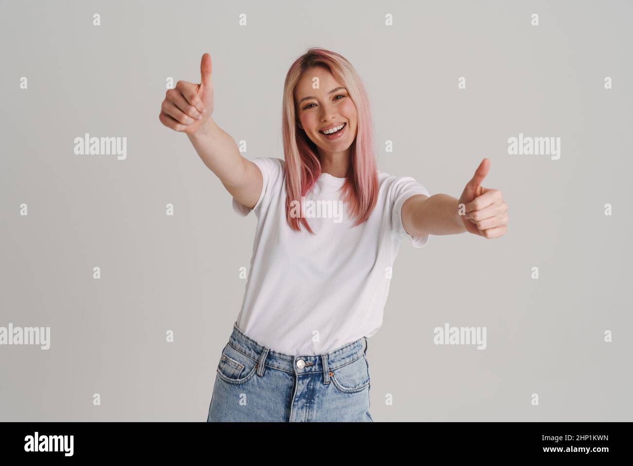 Young woman with pink hair smiling and gesturing thumb up isolated over ...