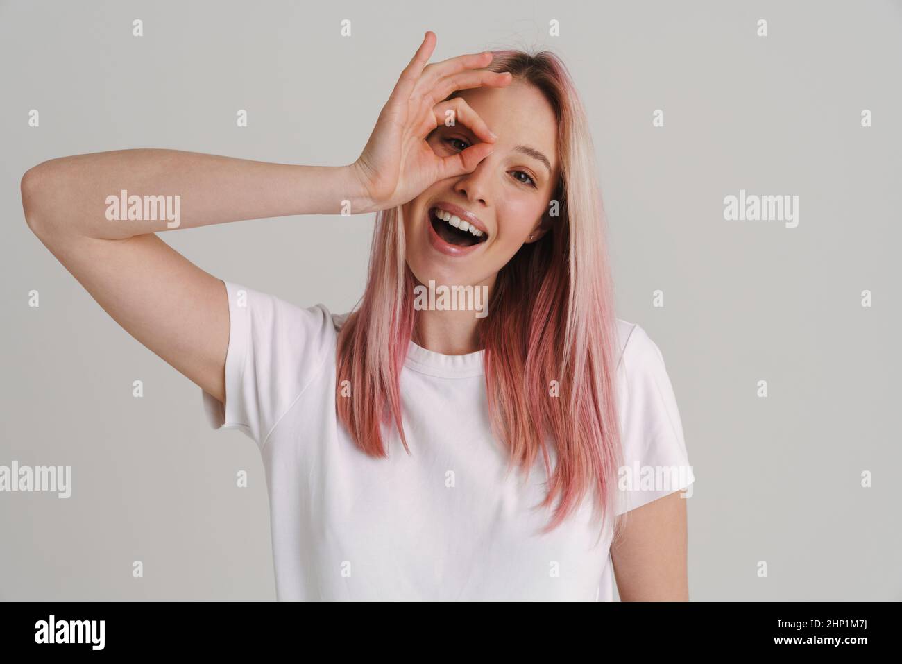 Young woman with pink hair smiling and gesturing ok sign isolated over ...
