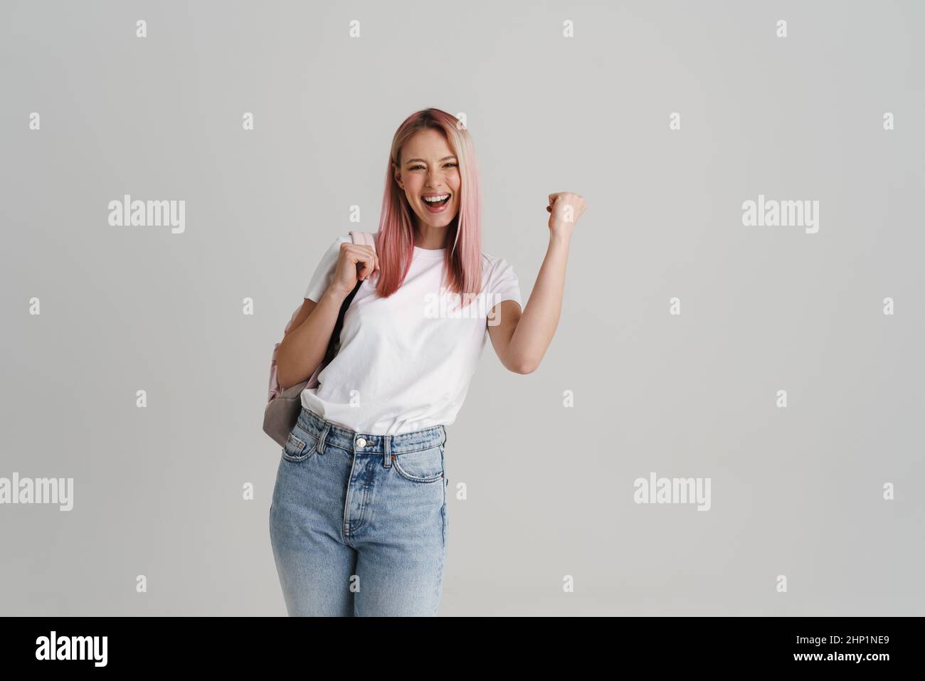 Young excited woman with backpack making winner gesture isolated over ...