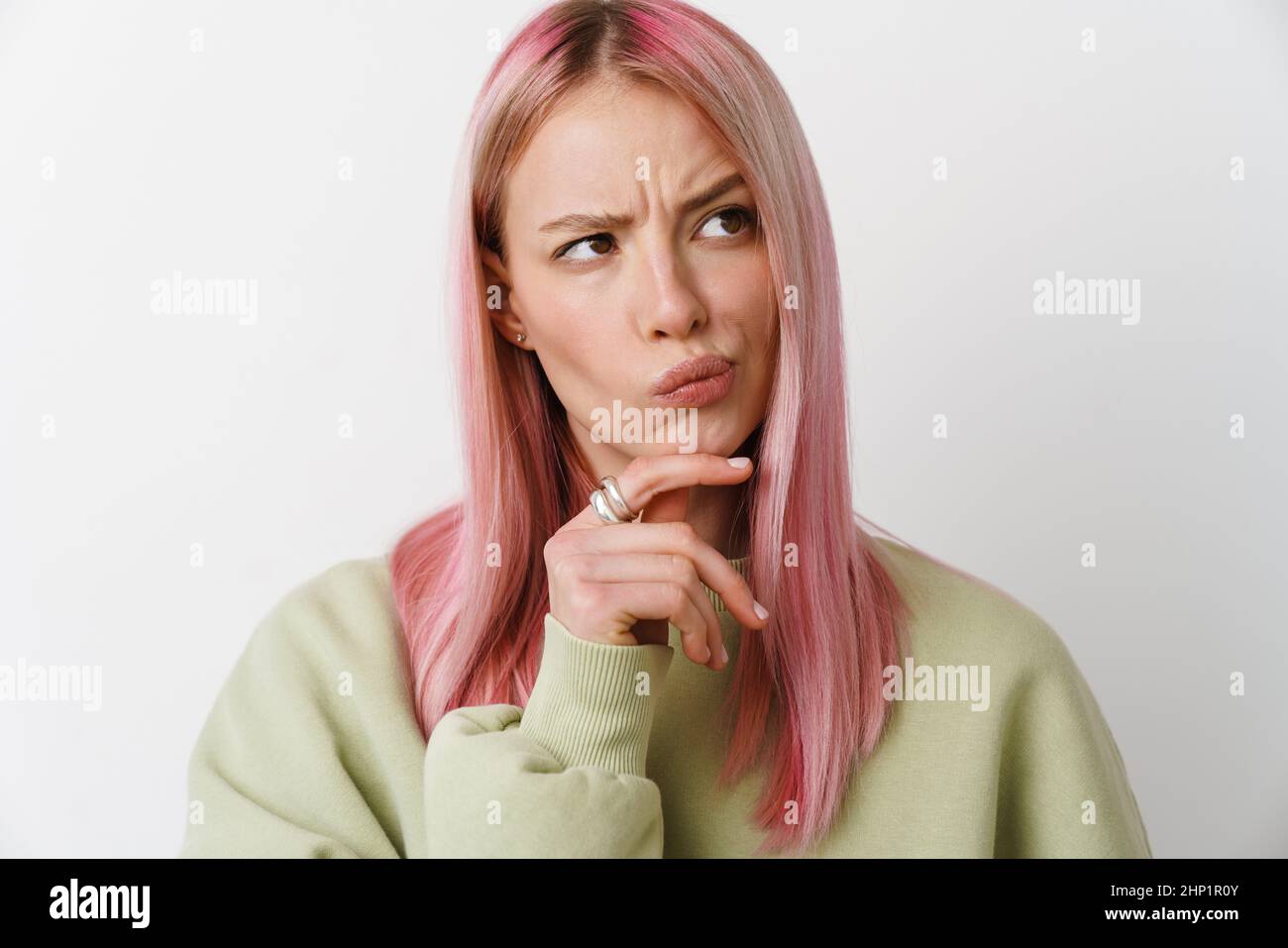 Young puzzled woman with pink hair frowning and looking upward isolated ...