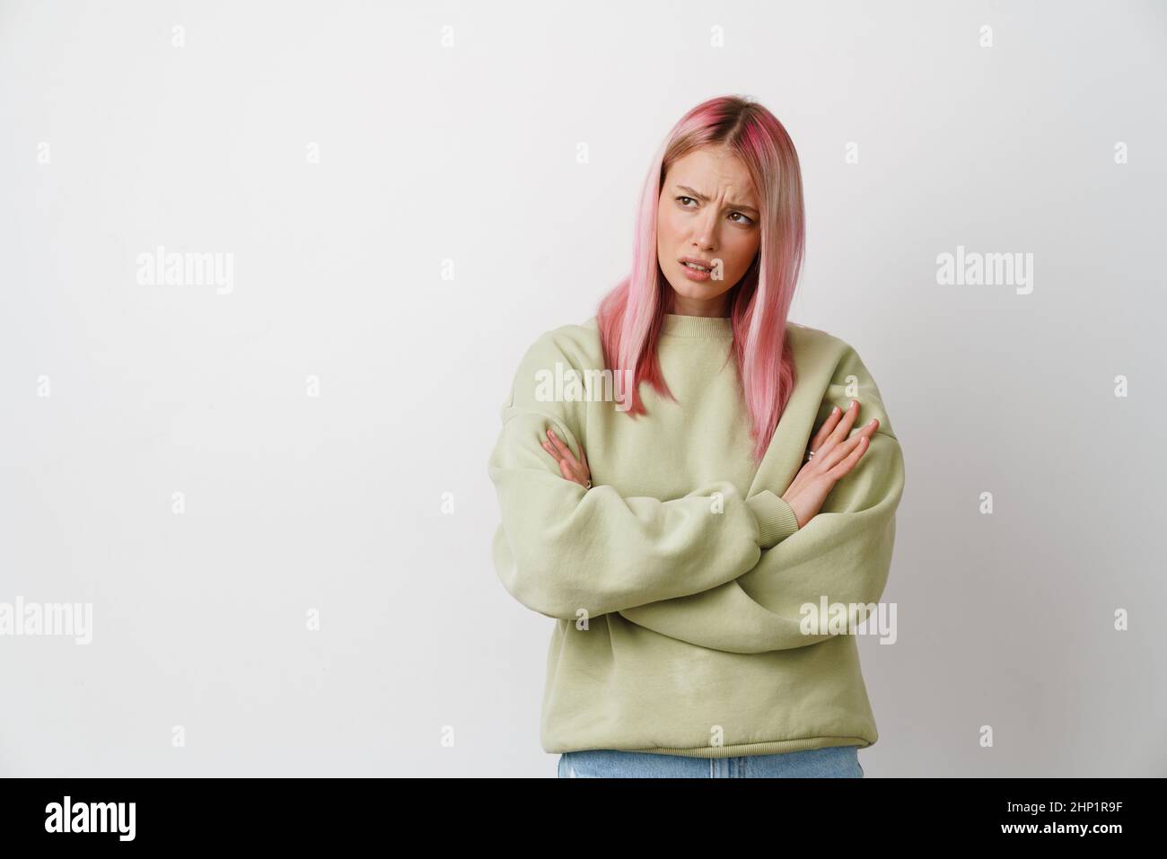 Young displeased woman with pink hair frowning and looking aside ...