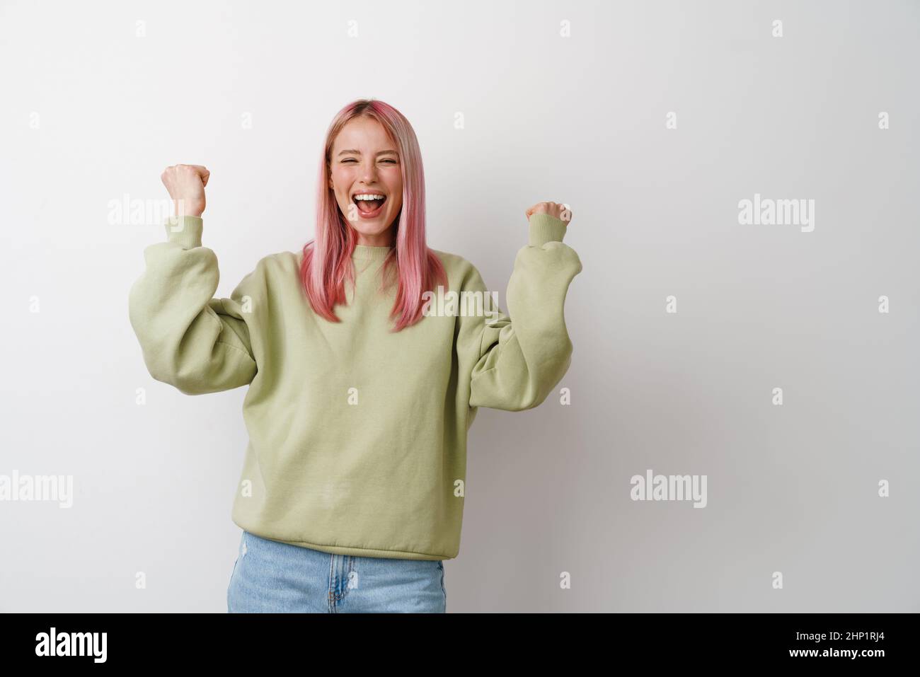 Young excited woman screaming and making winner gesture isolated over ...