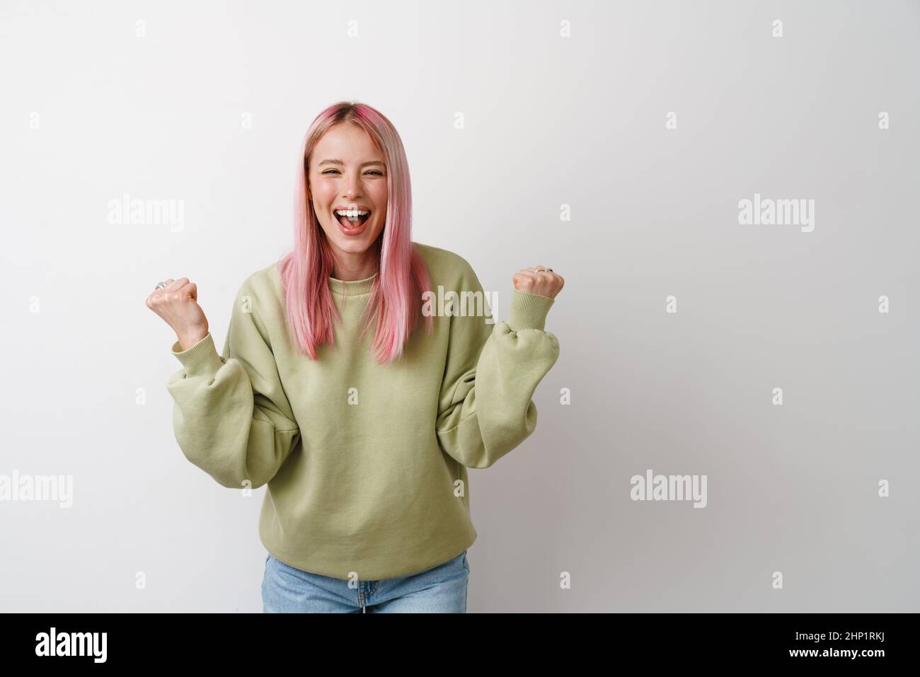 Young excited woman screaming and making winner gesture isolated over ...