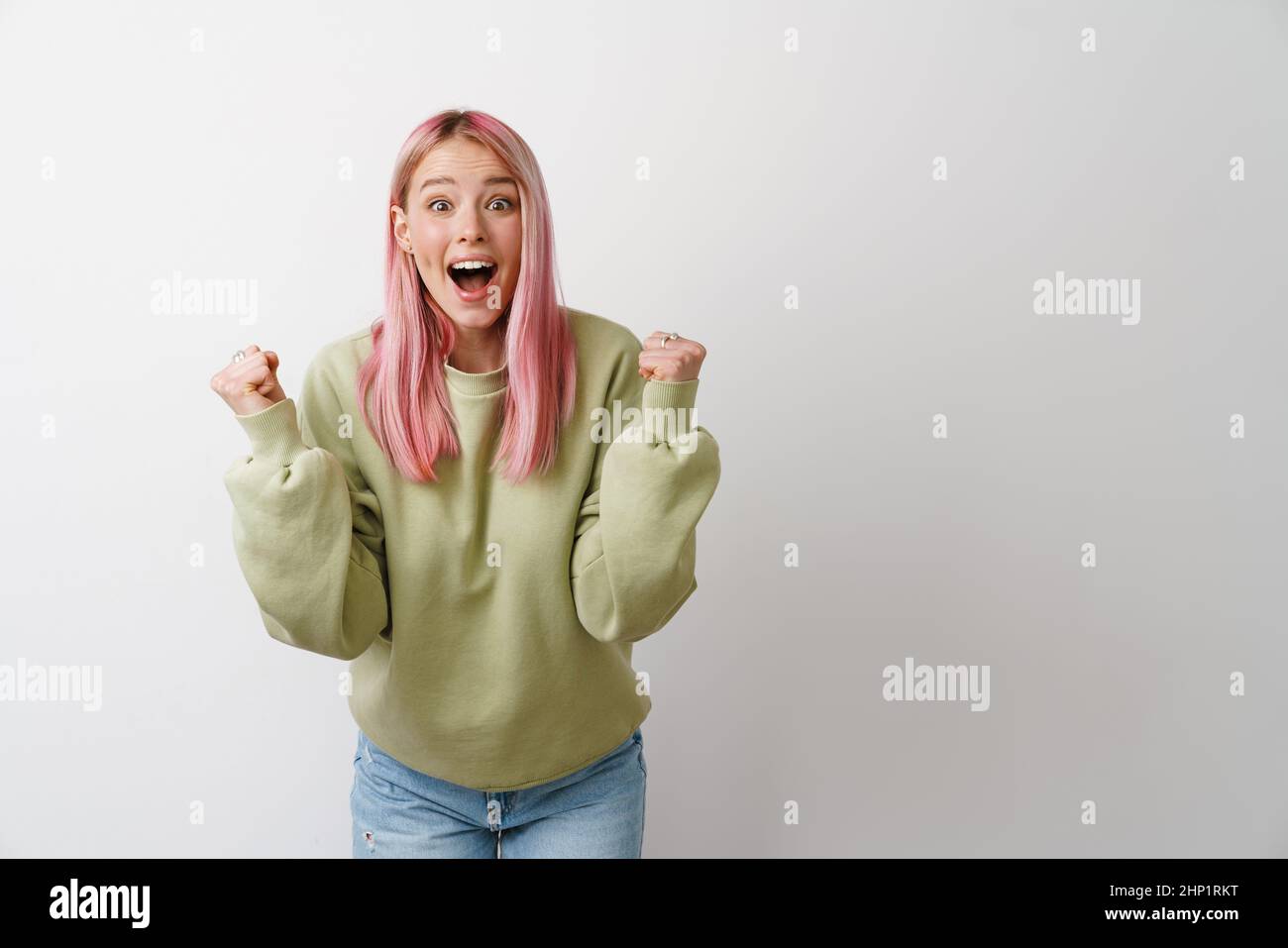 Young excited woman screaming and making winner gesture isolated over ...