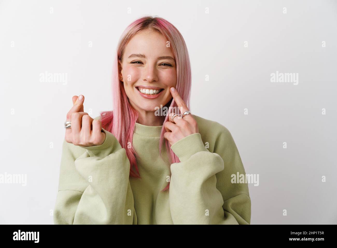 Young smiling woman gesturing and pointing finger at her cheek isolated ...
