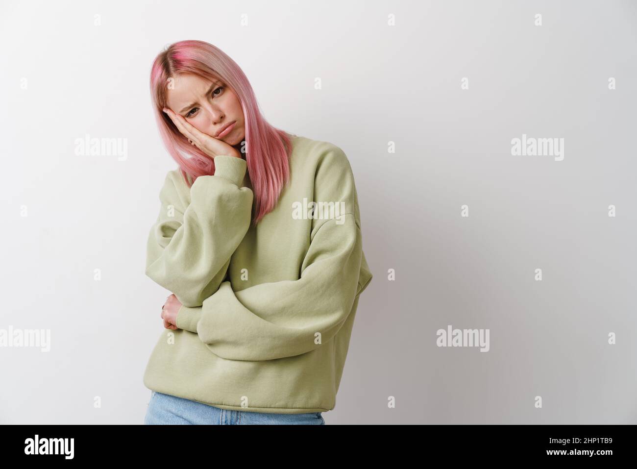 Young sad woman looking at camera while propping up her head isolated ...