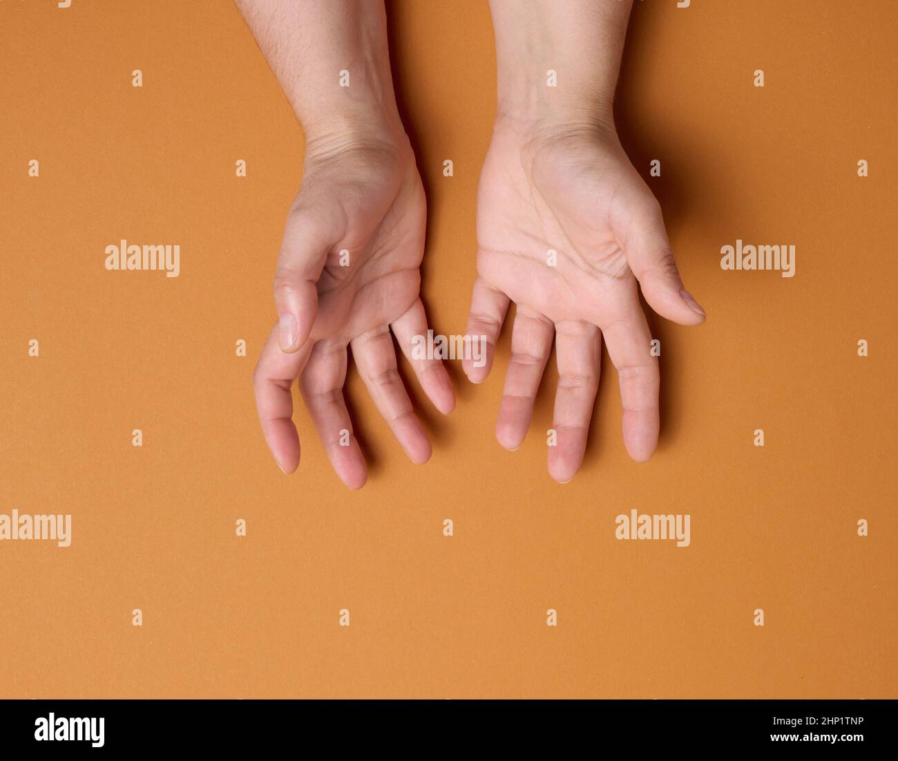 two female hands on a brown background. Empty palms open, top view ...