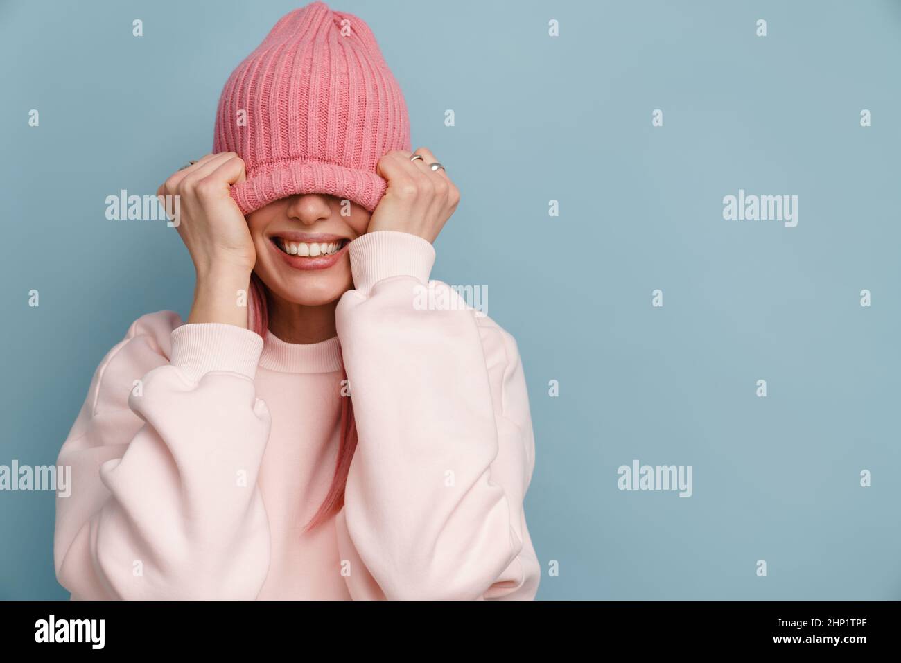 Young white woman with pink hair smiling and pulling hat down over her ...