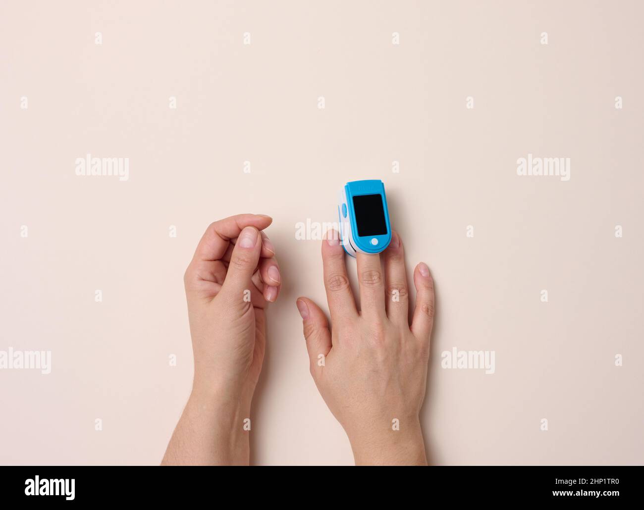 oximeter on a female finger, beige background. Blood oxygen measurement ...