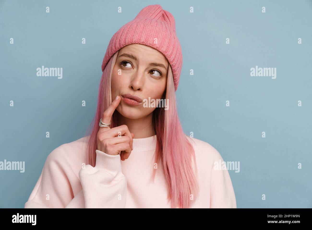 Young white woman with pink hair thinking and looking upward isolated ...