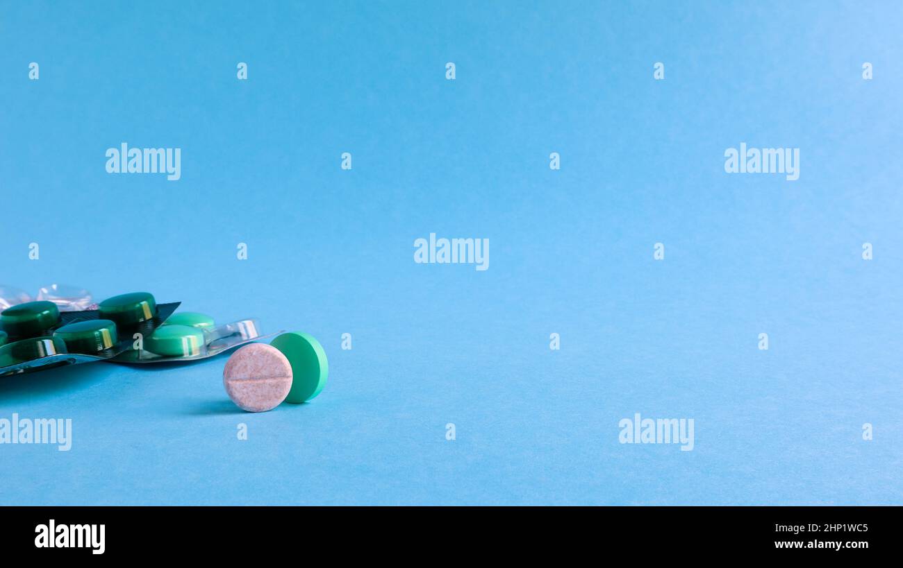 Two packs of pills and one round pill to the side on a blue background ...