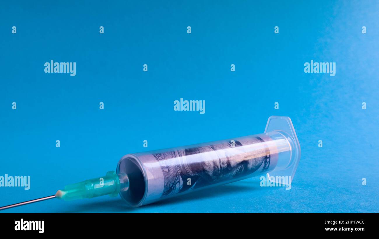 A roll of 100 dollars money inserted into a white medical hypodermic ...