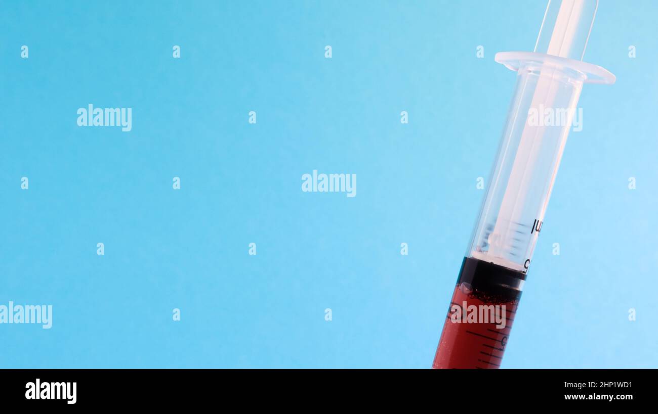 On a blue background lies a medical syringe with a needle. epidemic ...