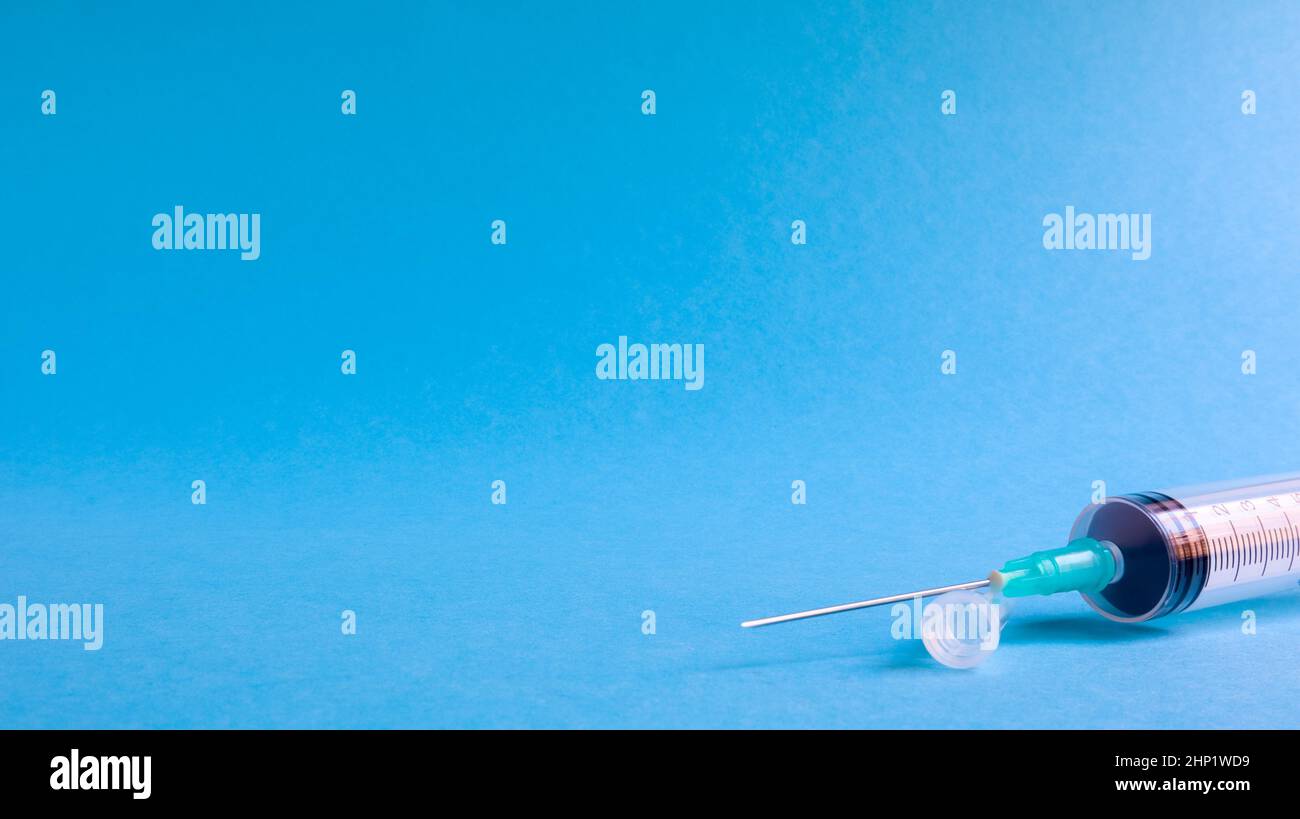On a blue background lies a medical syringe with a needle. epidemic ...