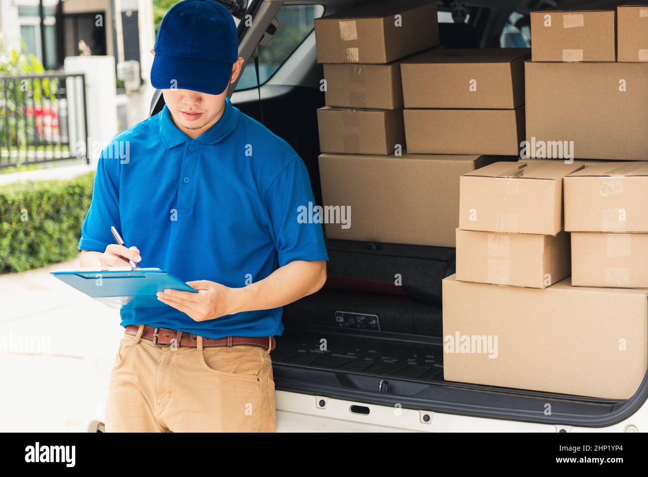 Asian young delivery man courier in uniform hold documents clipboard ...