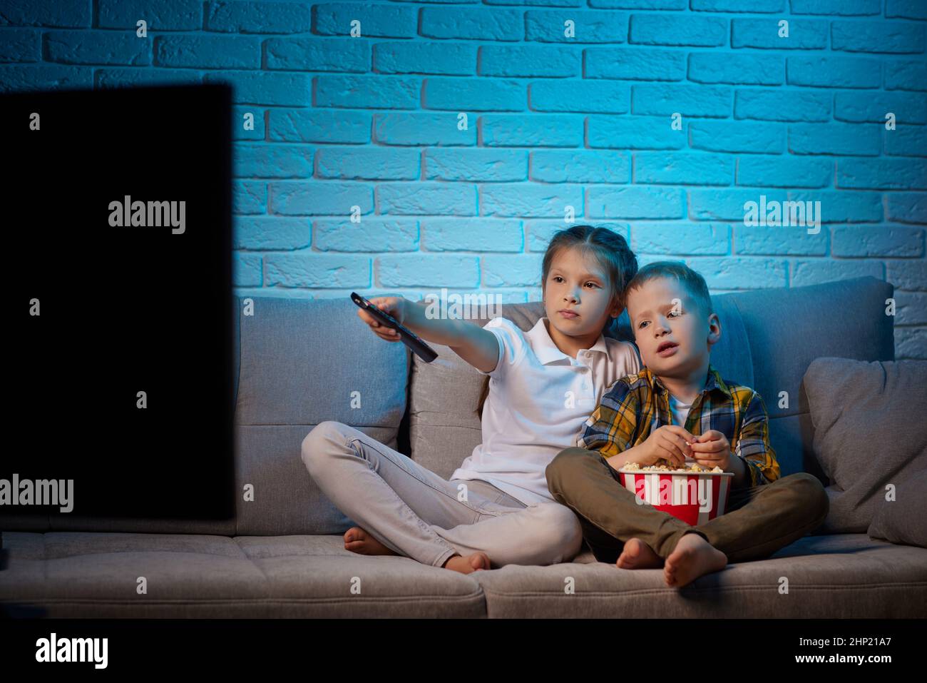 children with remote control sitting on couch and watching TV Stock ...