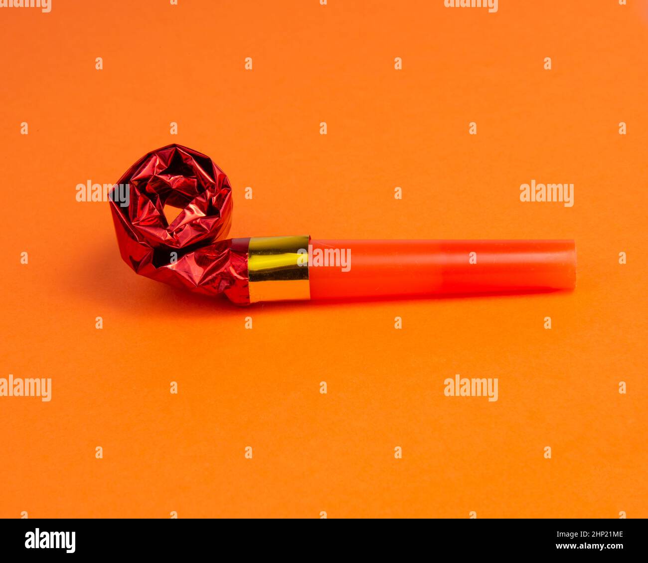Party foil red horn noisemaker for carnival on the orange background ...