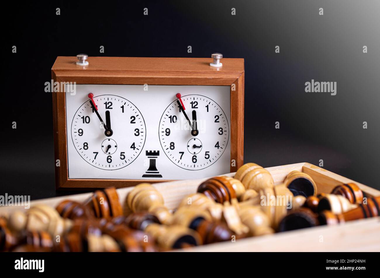 The Chess pieces on a board and a chess clock on a dark background Stock Photo - Alamy