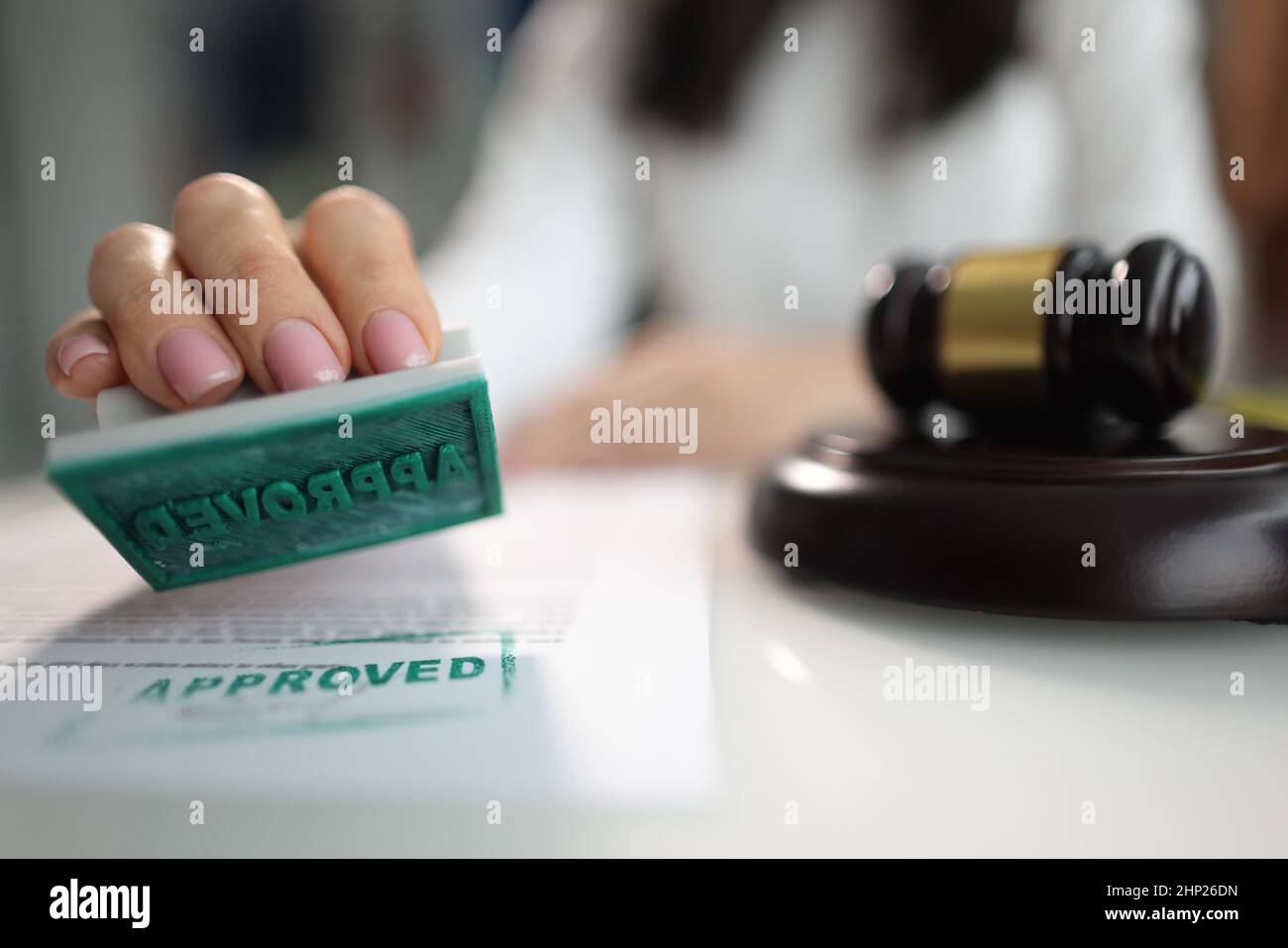 Hand puts stamp approved on document near judge's gavel Stock Photo - Alamy