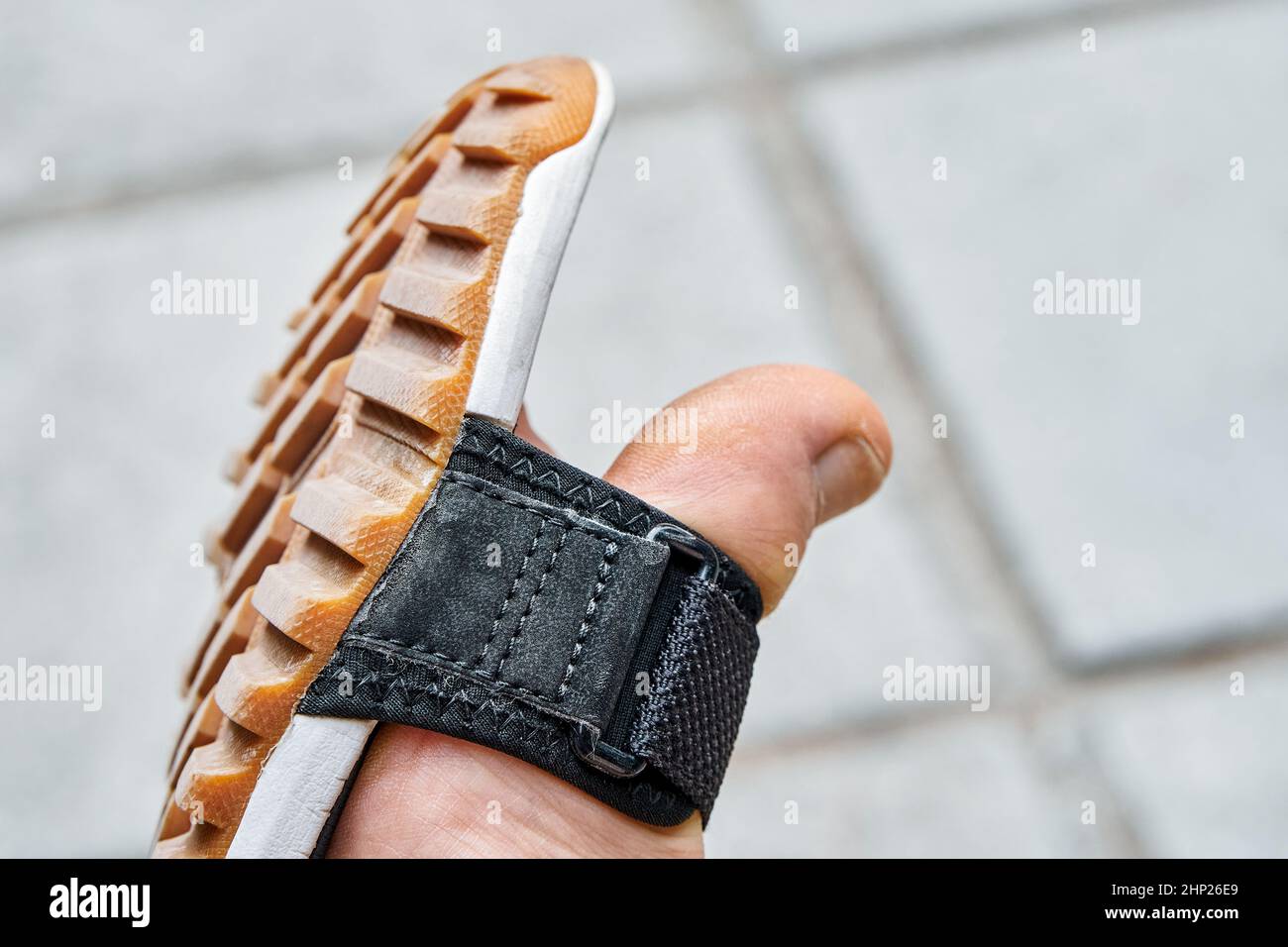 Toe of boy foot in black sandal with grooved sole. Boy raises leg above ...