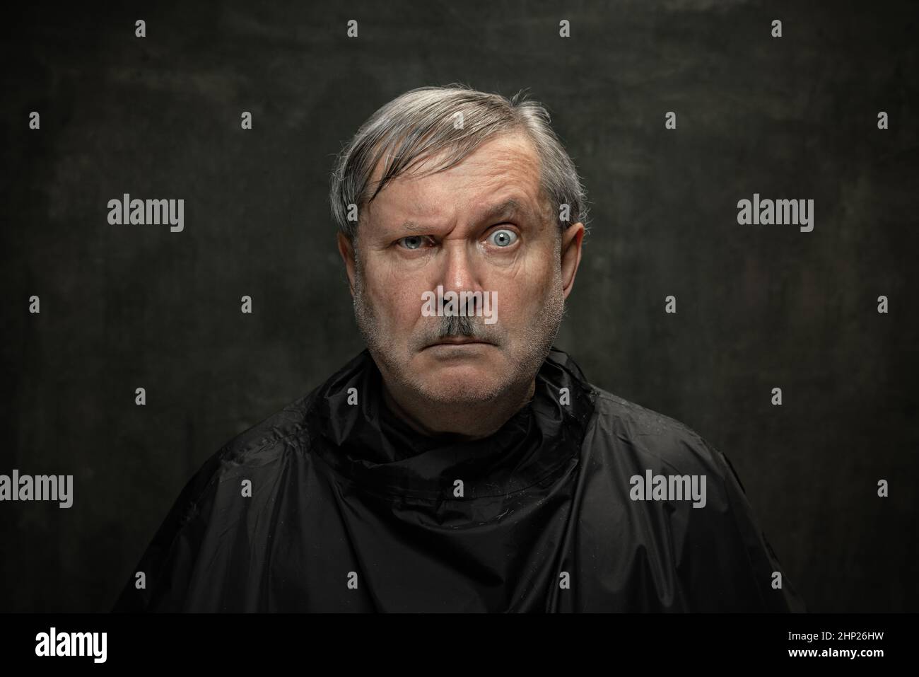 Portrait of angry senior man looking at camera isolated on dark vintage ...