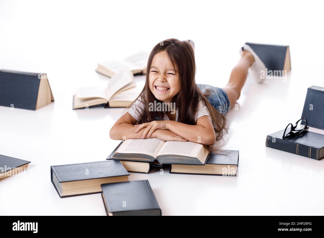 cute funny little child girl in denim is reading book on the floor with ...