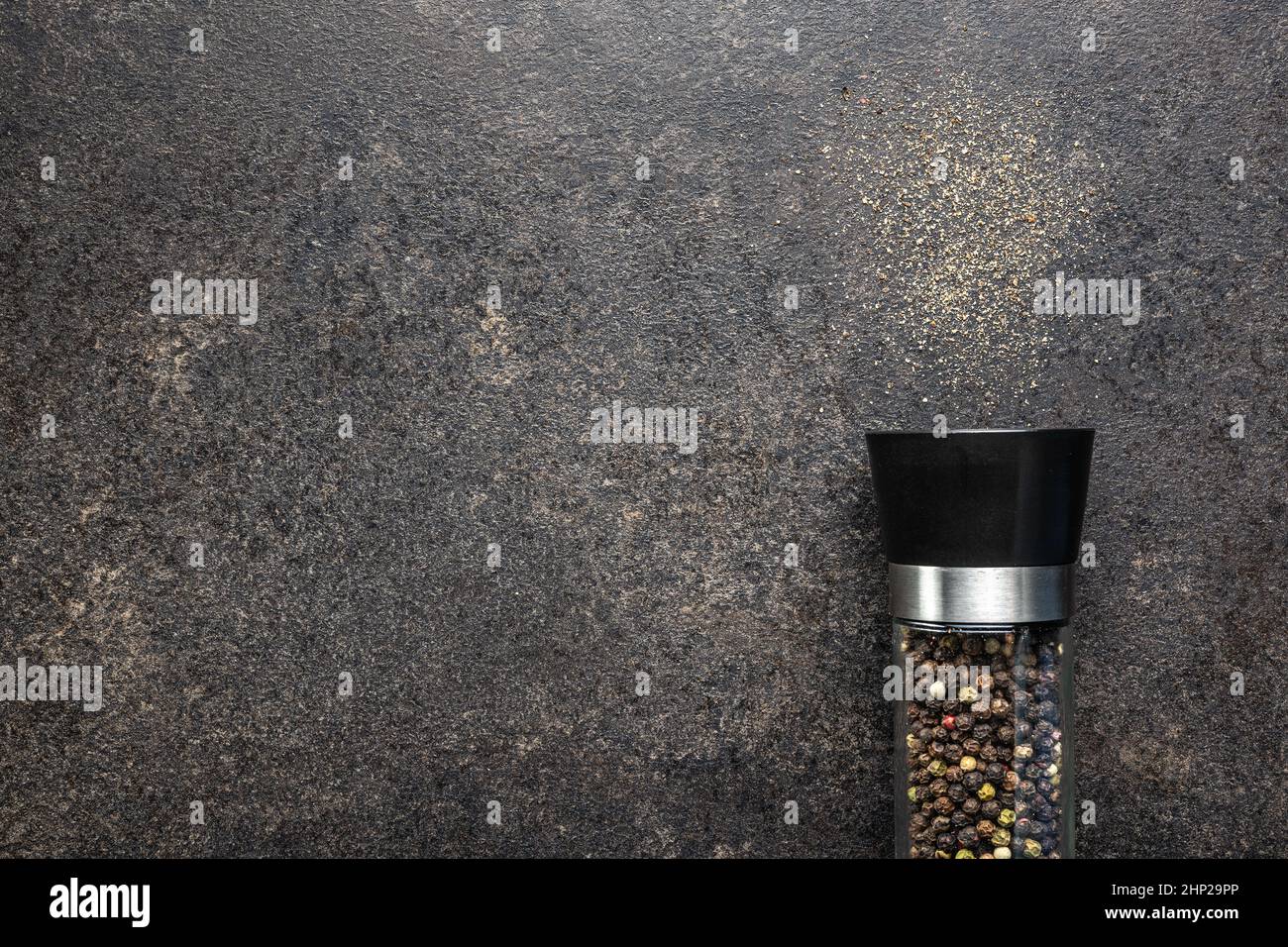 Pepper mill and ground pepper on black table. Top view Stock Photo - Alamy