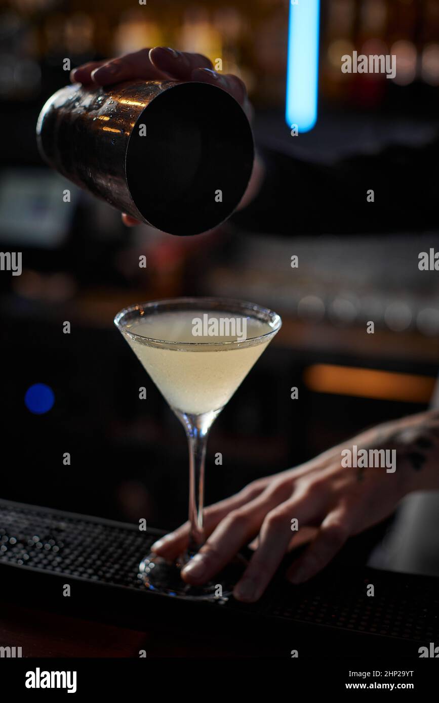male barman hands is making cocktail with steel shaker at the bar ...