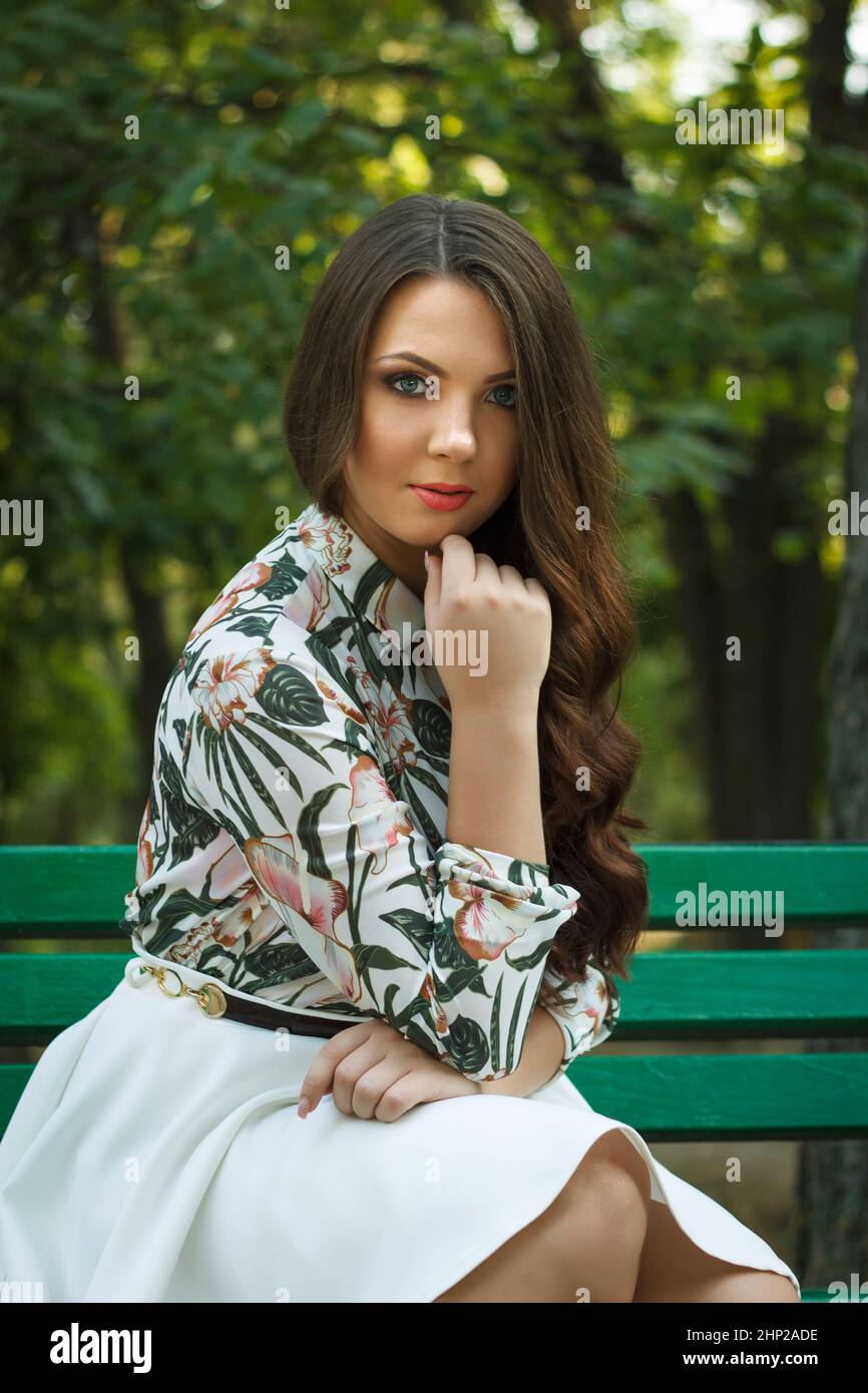 Beautiful brunette girl poses and relaxed on bench outdoors Stock Photo ...