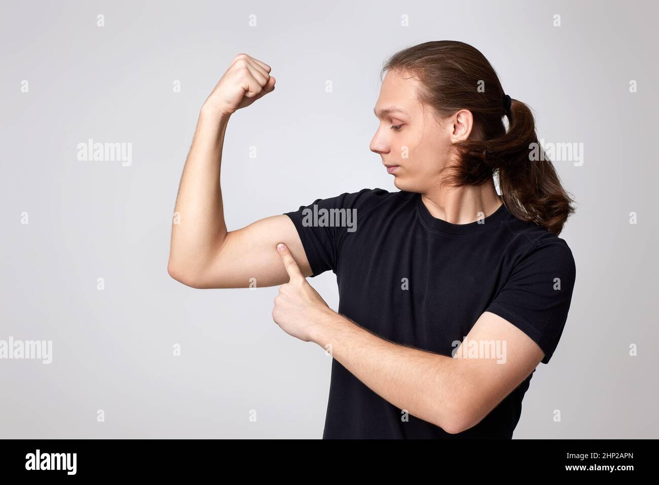 young fitness strong man show biceps muscles on hand isolated on gray ...