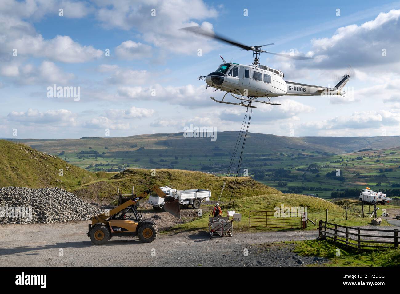 Helicopter carrying a load of stone to take up onto moorland to be used ...