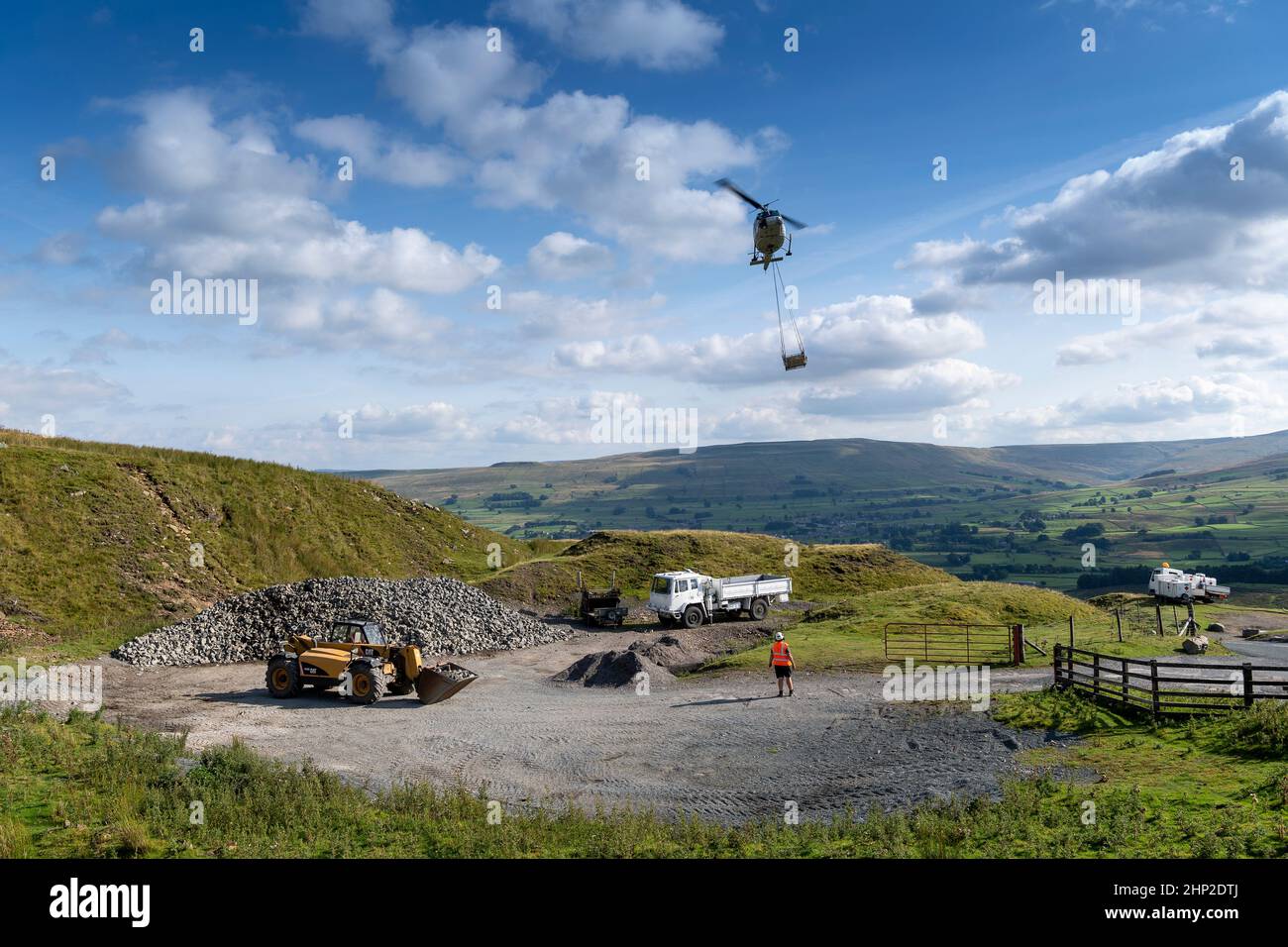 Helicopter carrying a load of stone to take up onto moorland to be used ...