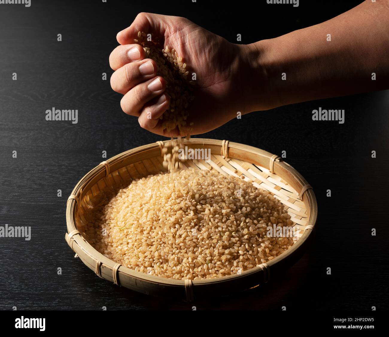The moment when a man pours brown rice into a bamboo colander placed on ...